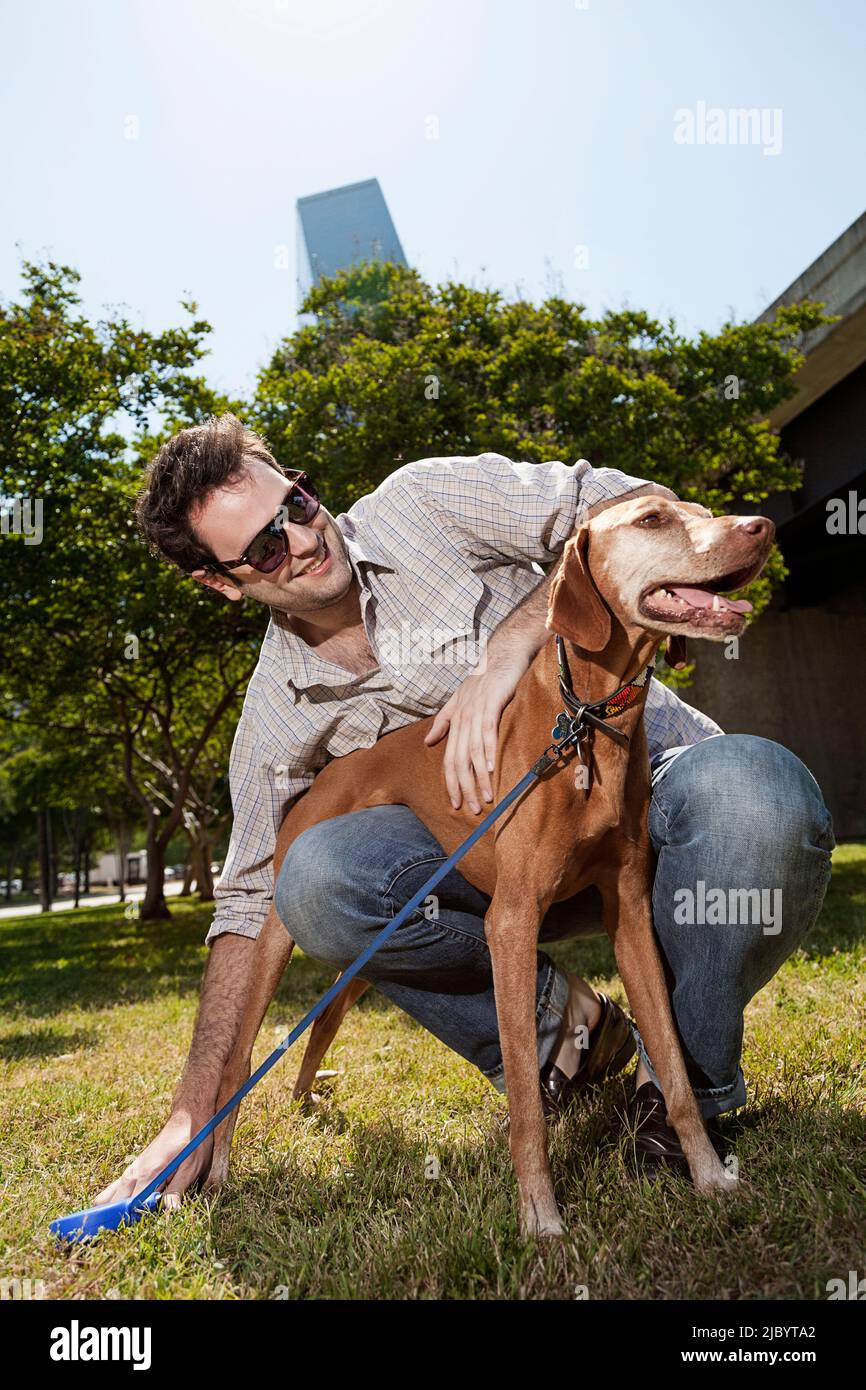 Man walking dog in urban park Stock Photo - Alamy