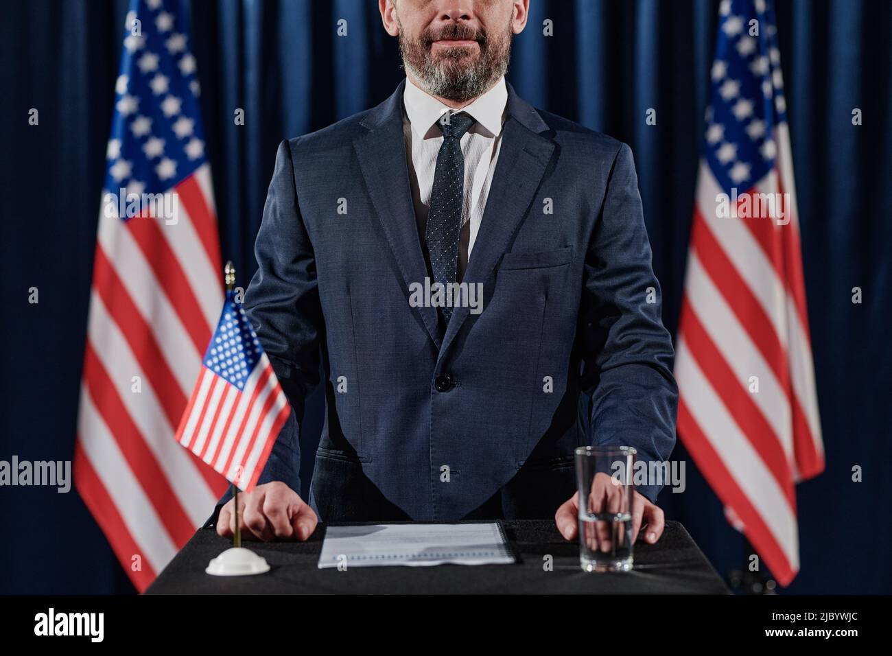 Portrait of male politician giving a speech standing on a stage with ...