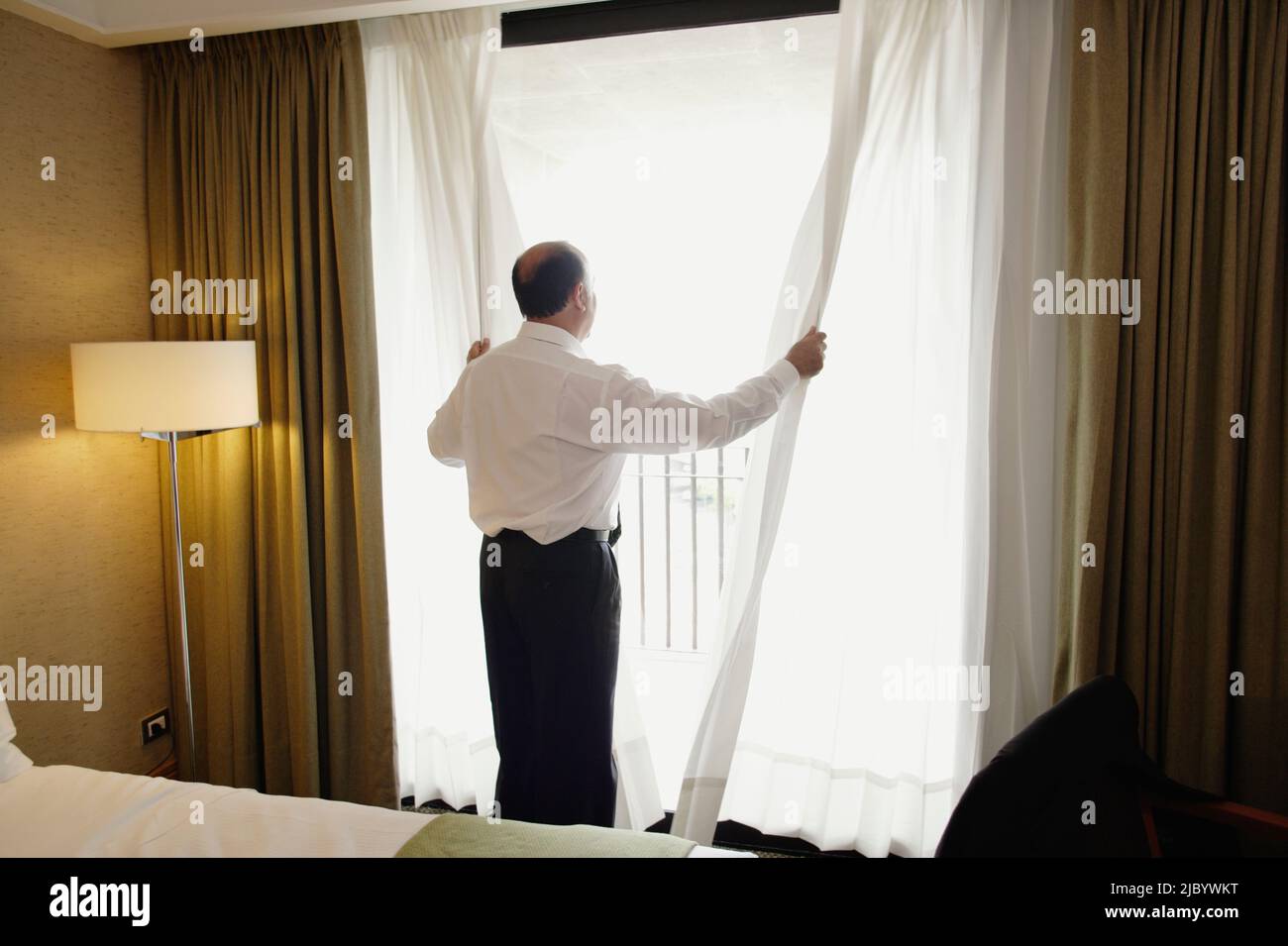 Man opening curtains in hotel room Stock Photo - Alamy