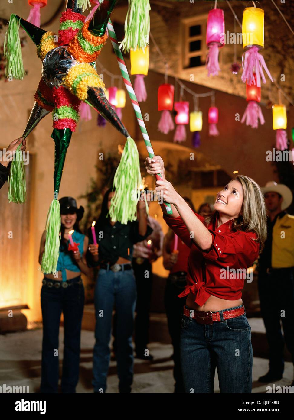 Mixed race woman hitting pinata Stock Photo - Alamy