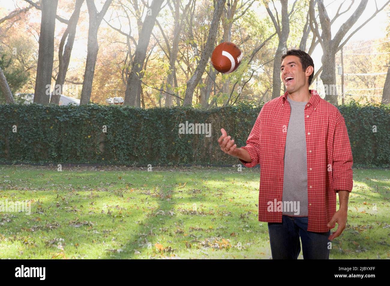 Caucasian man throwing football in backyard Stock Photo - Alamy