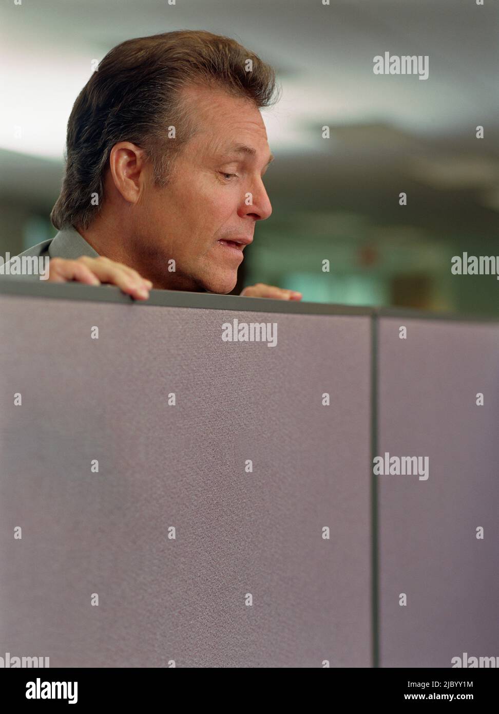 Businessman looking over cubicle wall Stock Photo - Alamy