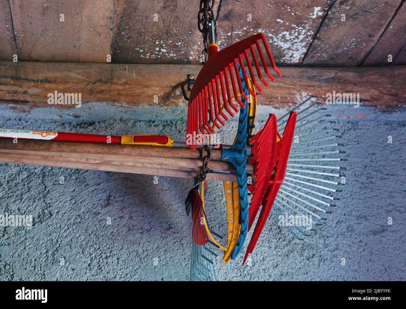 Colorful grass and leaves rakes hanging in the barn Stock Photo - Alamy