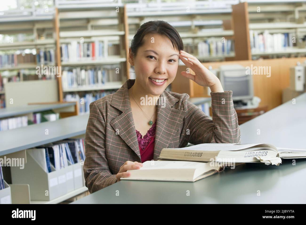 Young female asian student with books studying in library hi-res stock ...
