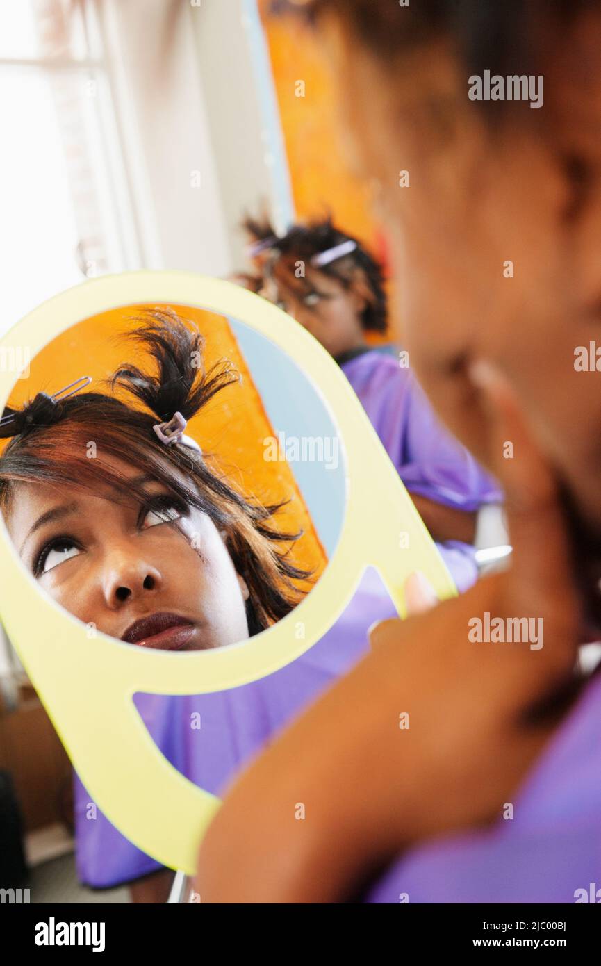 Young woman examining herself in the mirror Stock Photo - Alamy