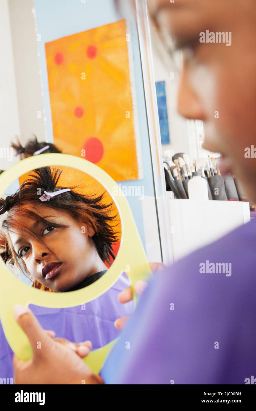 Young woman examining herself in the mirror Stock Photo - Alamy