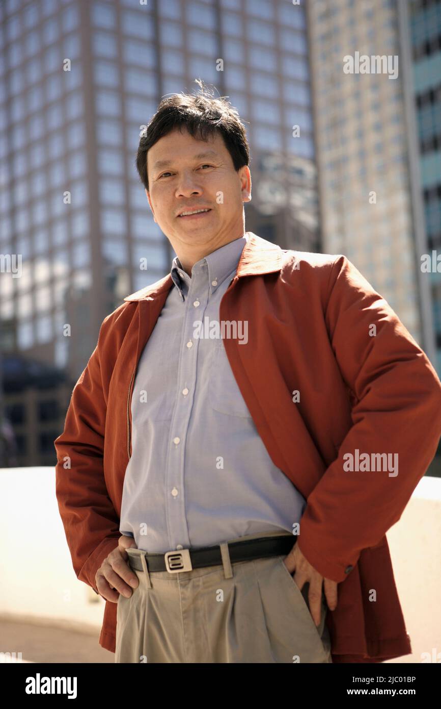 Asian man with hands on hips in urban area Stock Photo - Alamy
