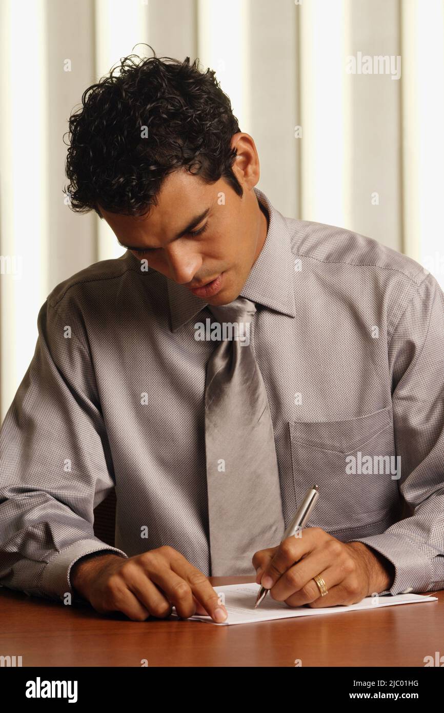 Hispanic businessman filling out paperwork Stock Photo - Alamy