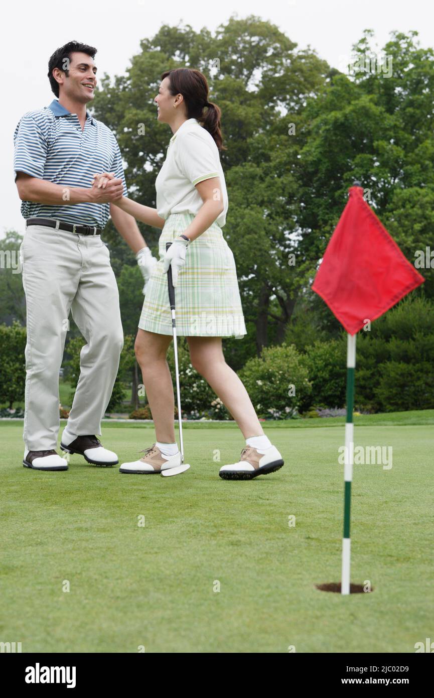 Couple shaking hands on golf course Stock Photo - Alamy