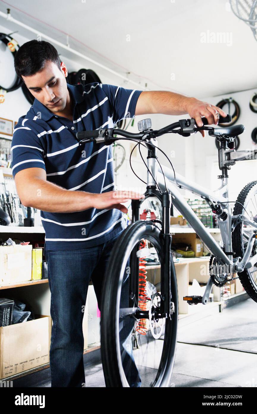 Man spinning wheel of bike in bike shop Stock Photo - Alamy