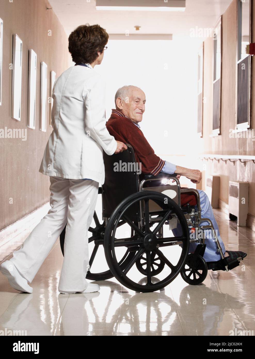 Nurse wheeling elderly man in wheelchair away Stock Photo - Alamy