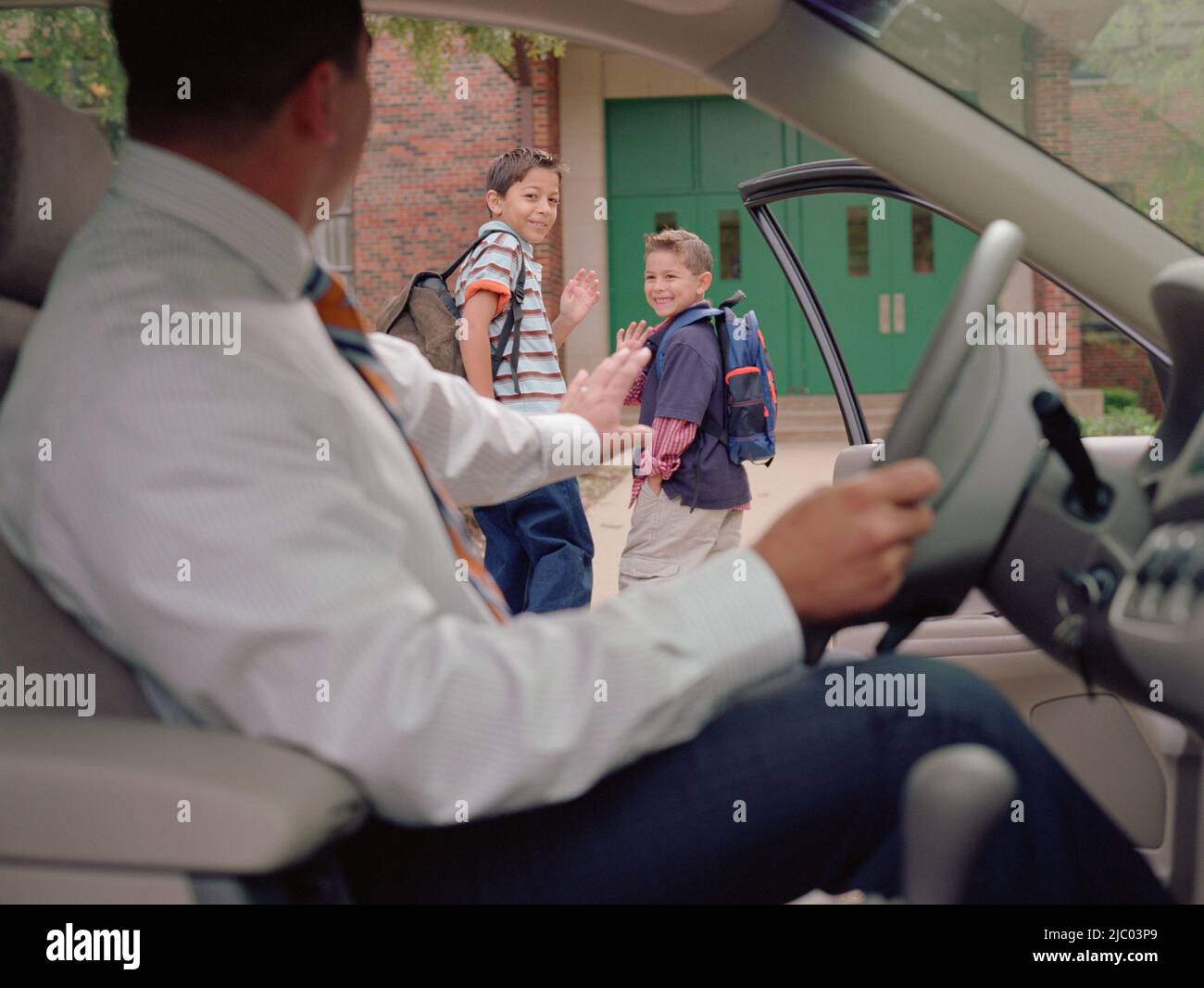 Young man waving his sons off to school Stock Photo - Alamy