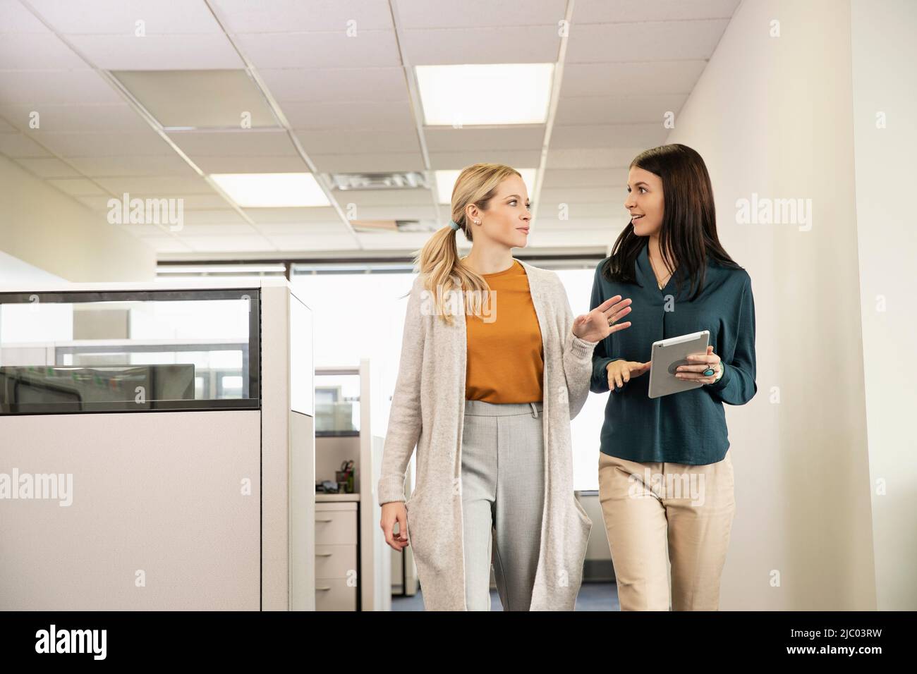 Two co-workers walking together in an office Stock Photo - Alamy