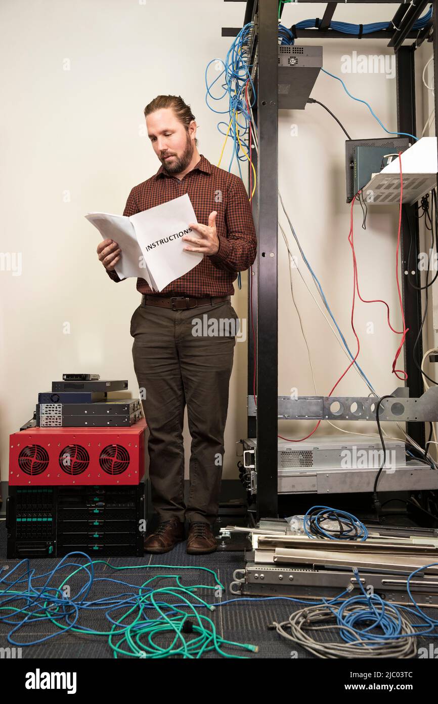 An IT employee looks confused while putting together a server Stock ...