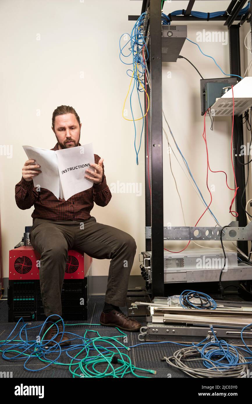 An IT employee looks confused while putting together a server Stock ...