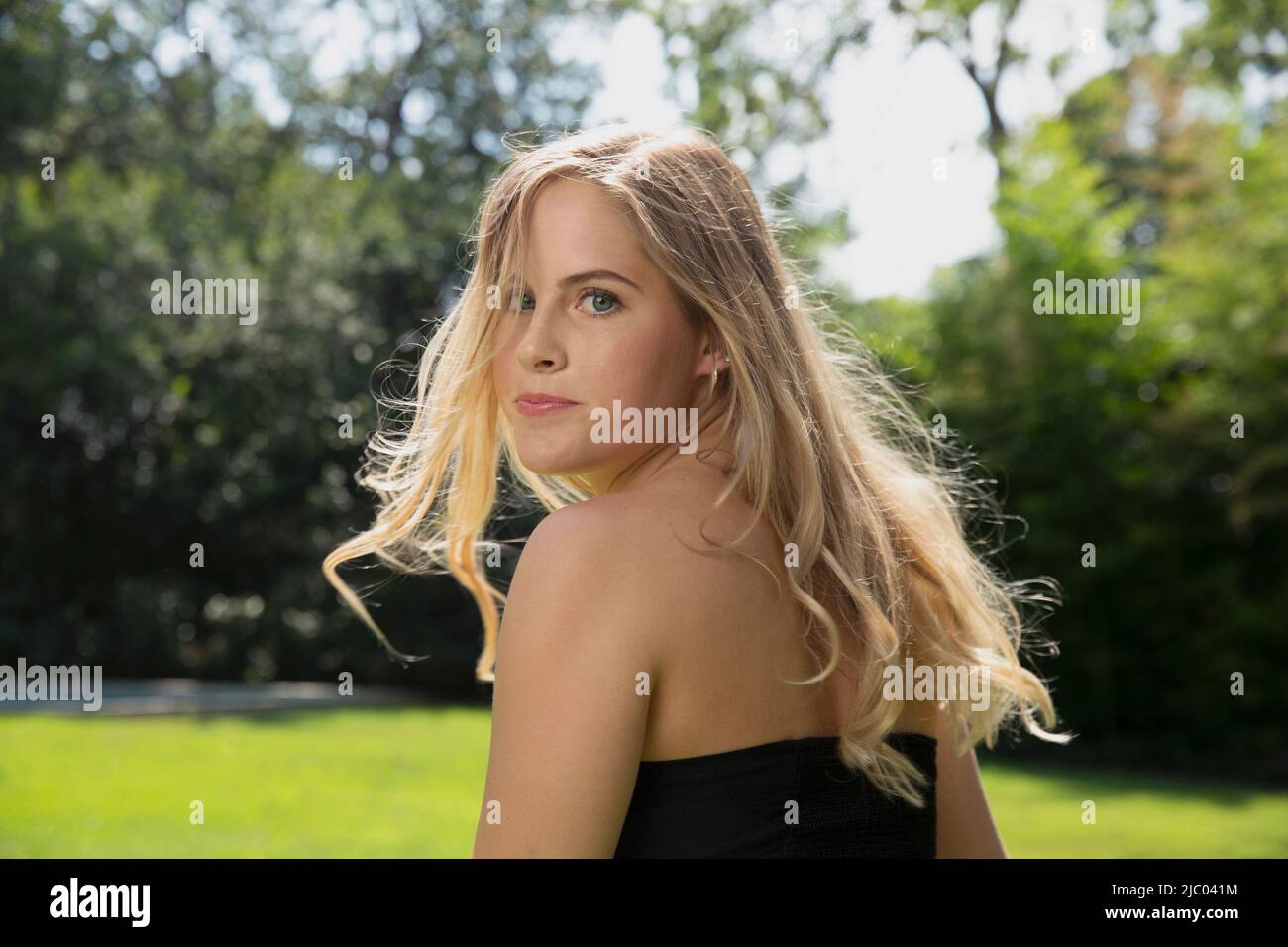 Young woman looking over her shoulder looking at camera Stock Photo - Alamy