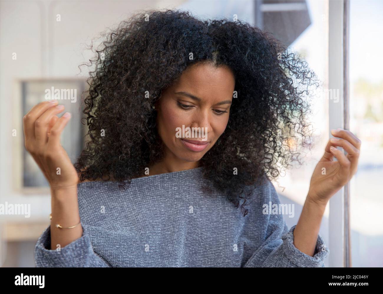 Mixed race, middle-aged woman brings her hands up to her natural hair Stock Photo - Alamy