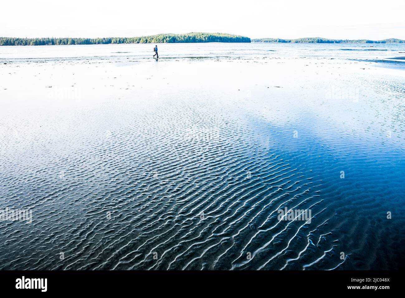 A woman walking and patterns at low tide on Tonquin Beach near Tofino ...