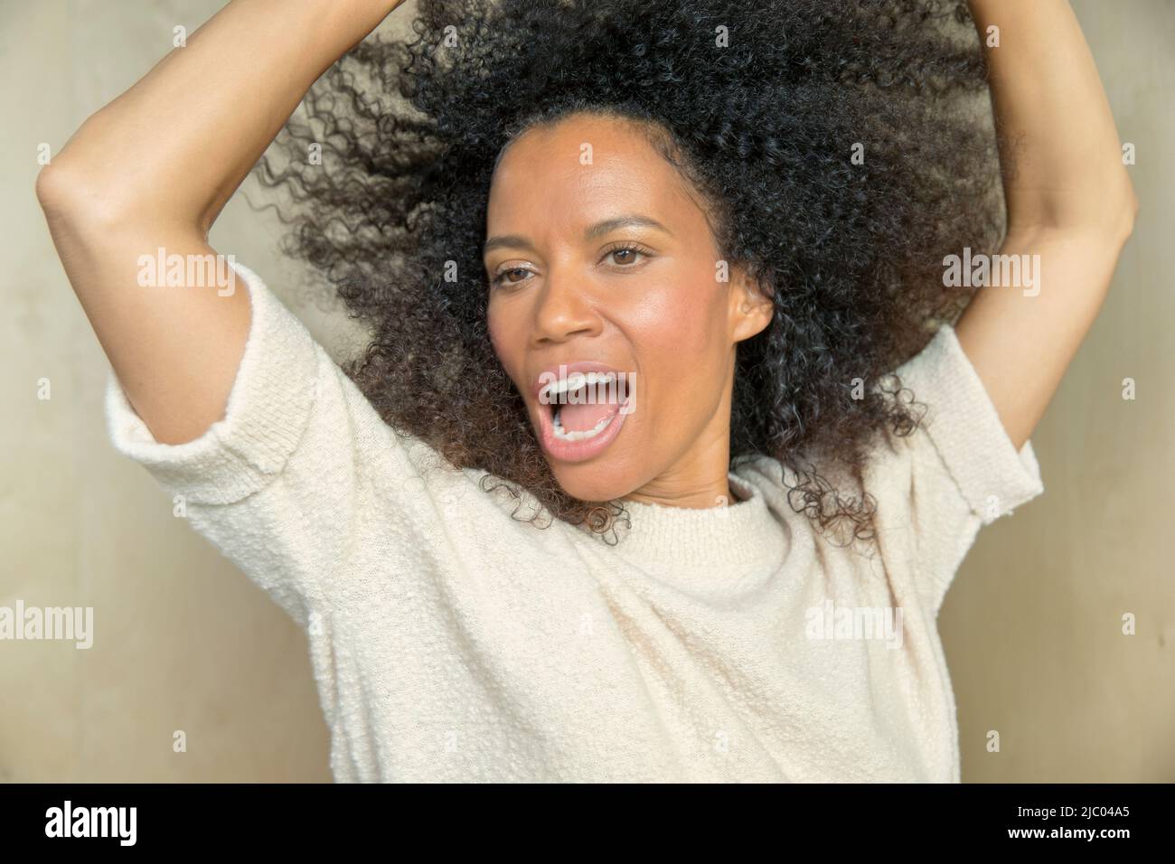 Close up portrait of a mixed race middle aged woman singing with her hands up in the air Stock ...