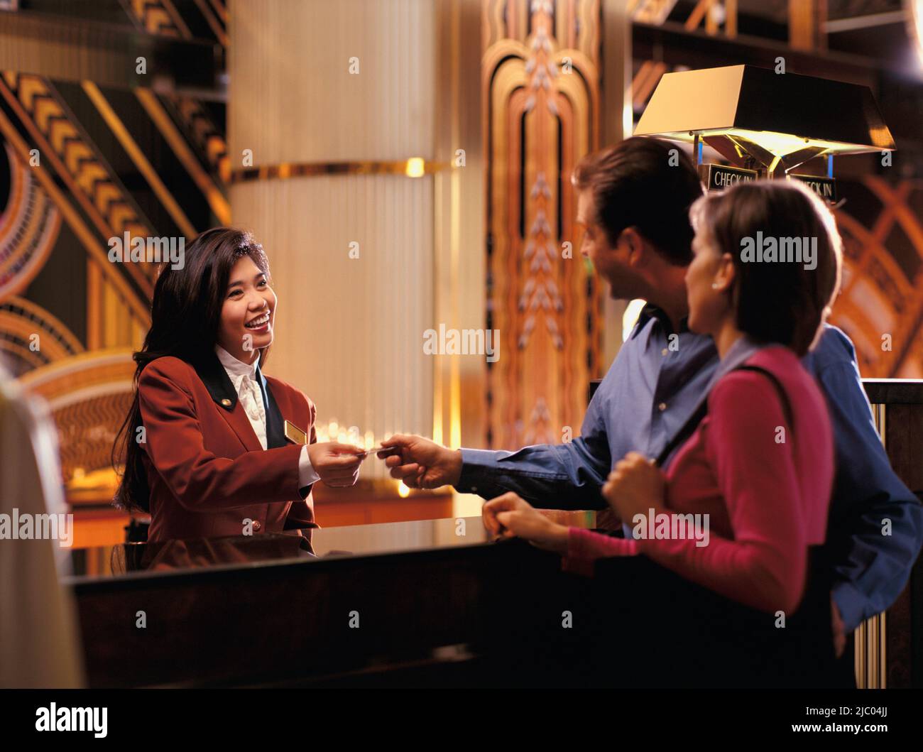 Female receptionist giving room key to couple Stock Photo - Alamy