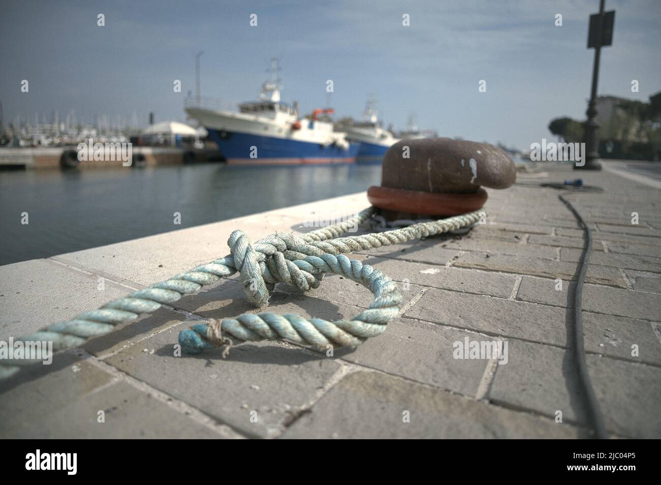 Port in Italy with a tied rope of a boat Stock Photo - Alamy