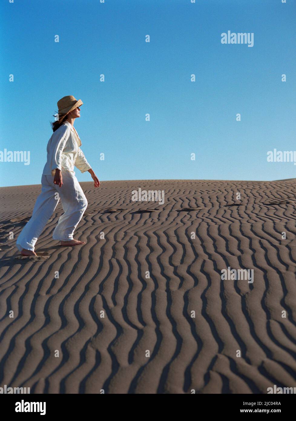 Young woman walking barefoot on sand Stock Photo - Alamy