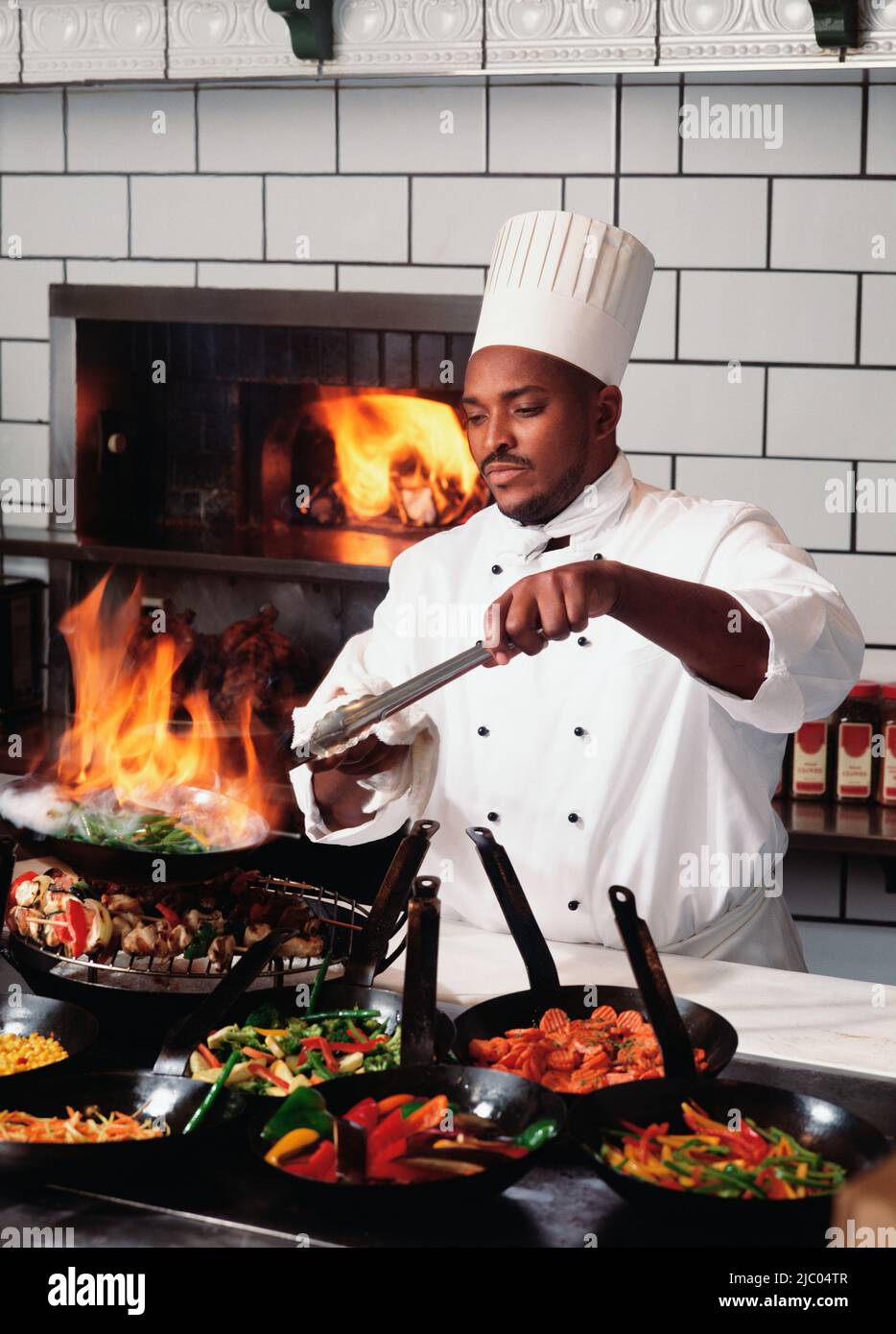 Male chef cooking food near fireplace Stock Photo - Alamy