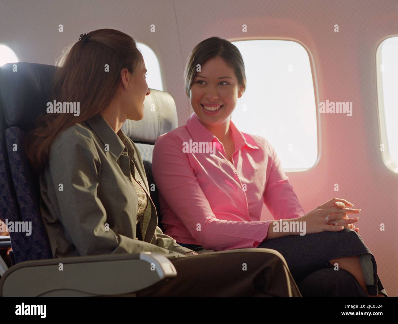 Young women talking on airplane Stock Photo - Alamy