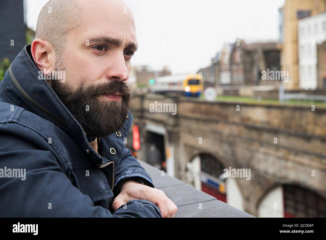 Man looking over ledge of building from rooftop patio Stock Photo - Alamy