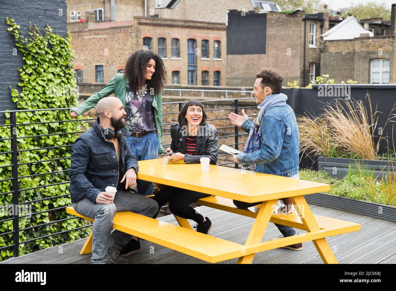 Group of friends working on tablets at outdoor patio table in co ...