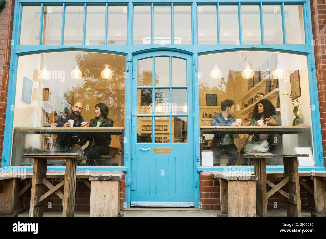 Friends sitting in window of cafe Stock Photo - Alamy