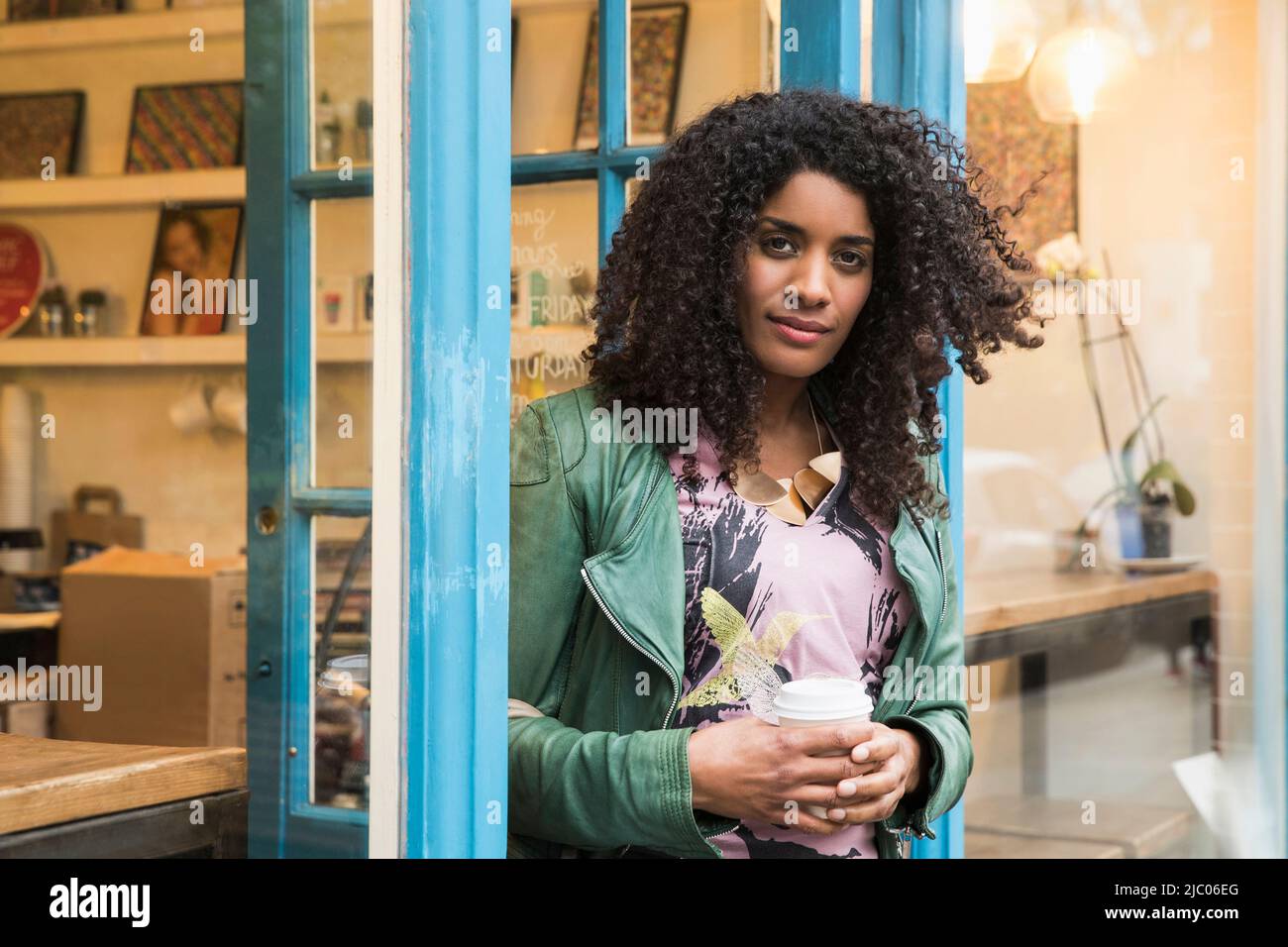 Woman walking out of cafe with coffee in hand Stock Photo - Alamy