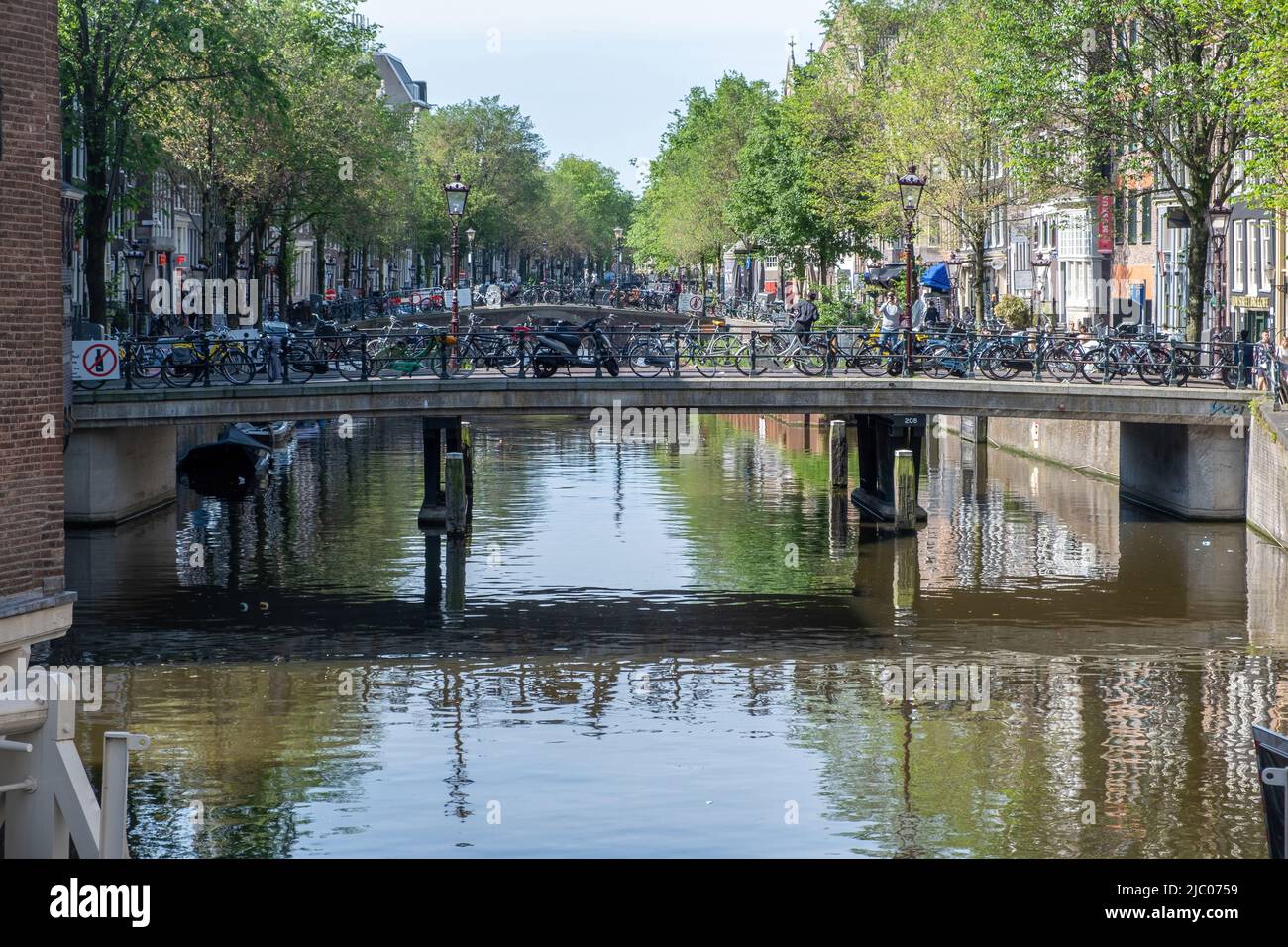 Amsterdam, Netherlands. Bridge over canal, people bike, parked bicycle ...