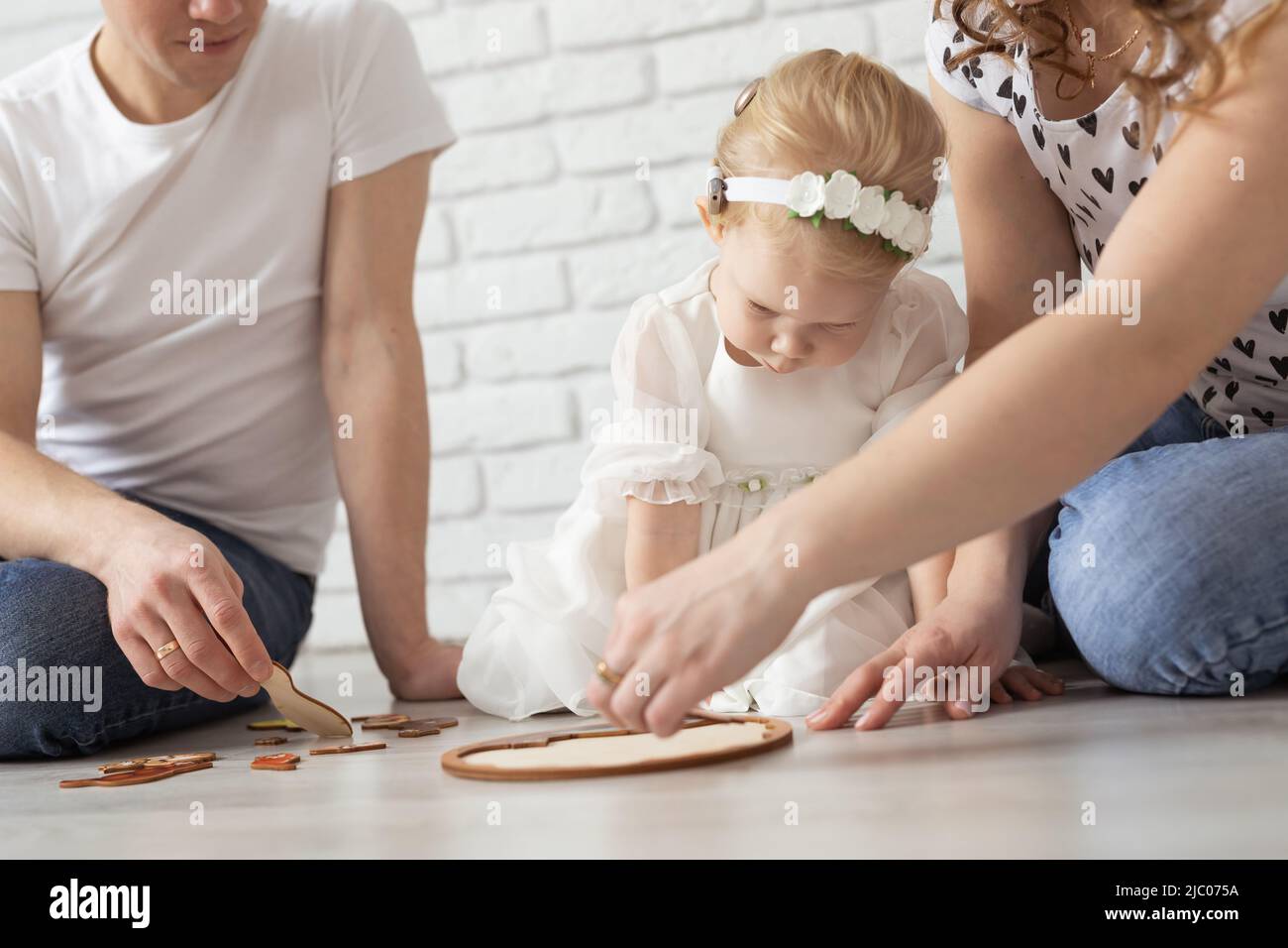 Baby child with hearing aids and cochlear implants plays with parents ...