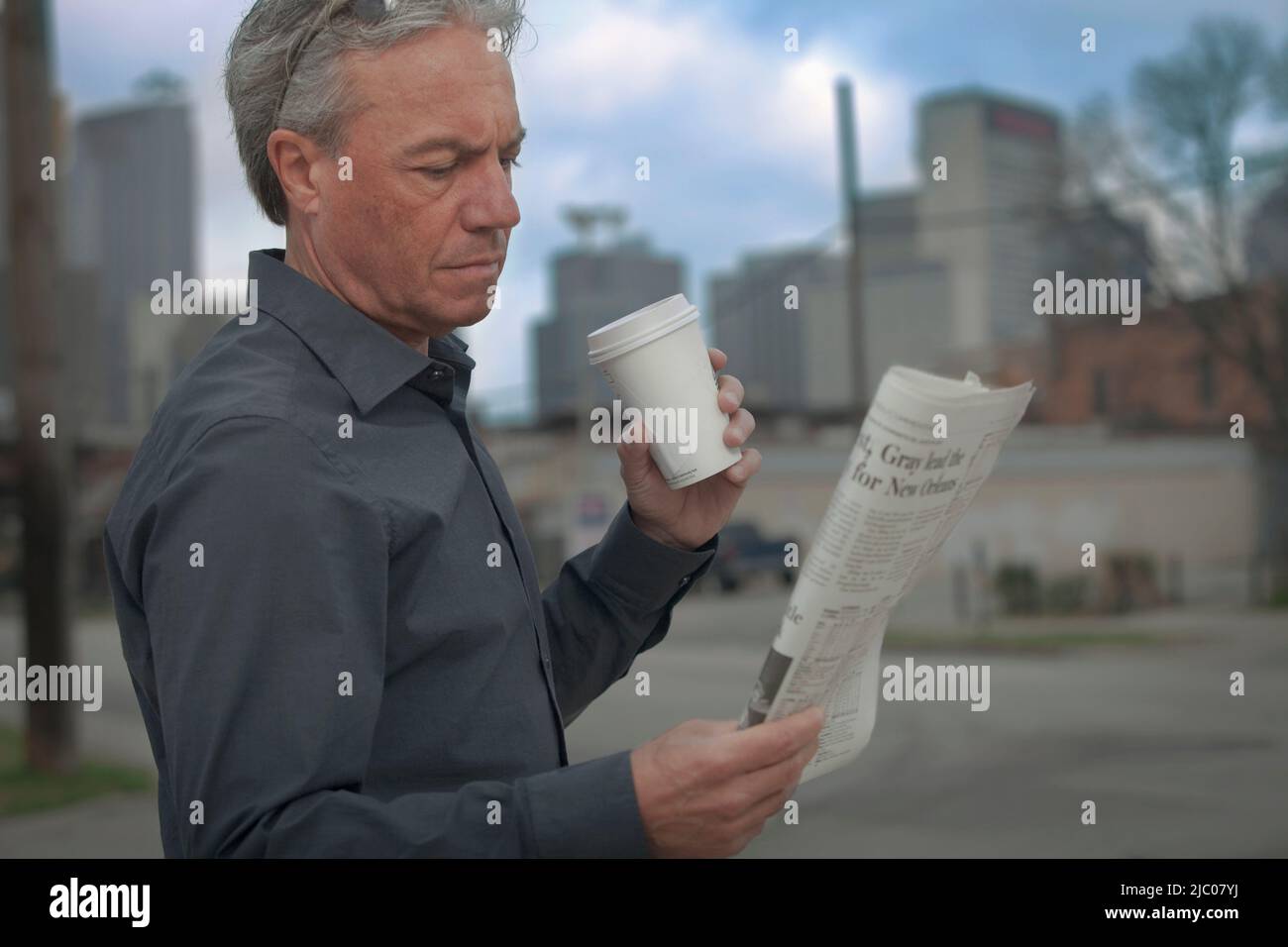 Man drinking coffee and reading a newspaper Stock Photo - Alamy