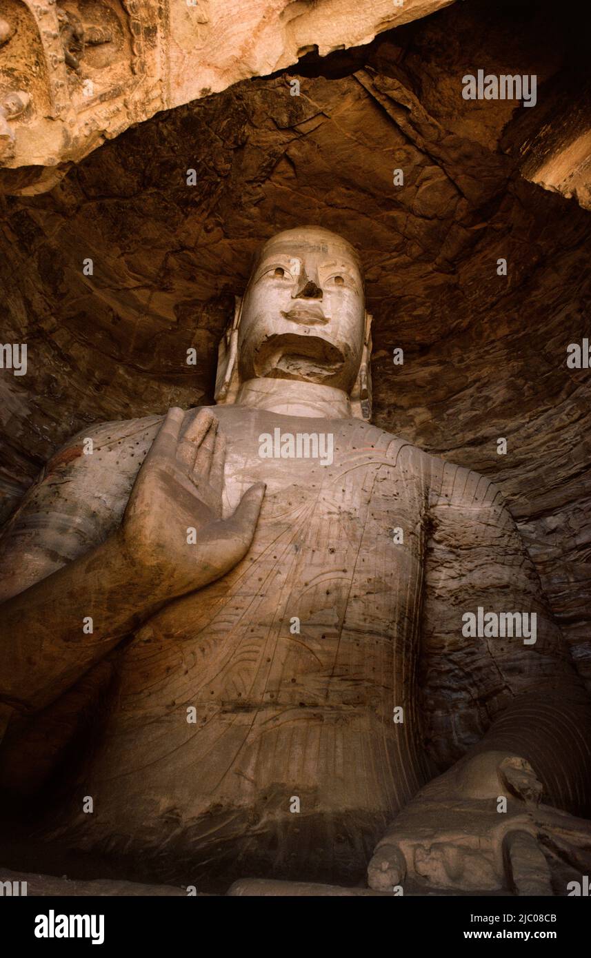 Low angle view of a Buddha statue in a cave, Yungang Buddhist Caves ...