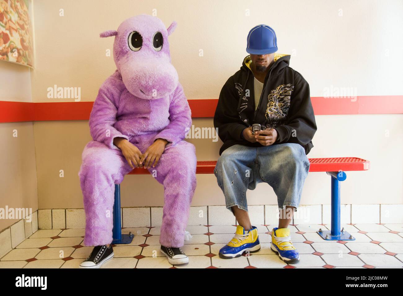 Person in hippo costume sitting next to a man text messaging on a ...