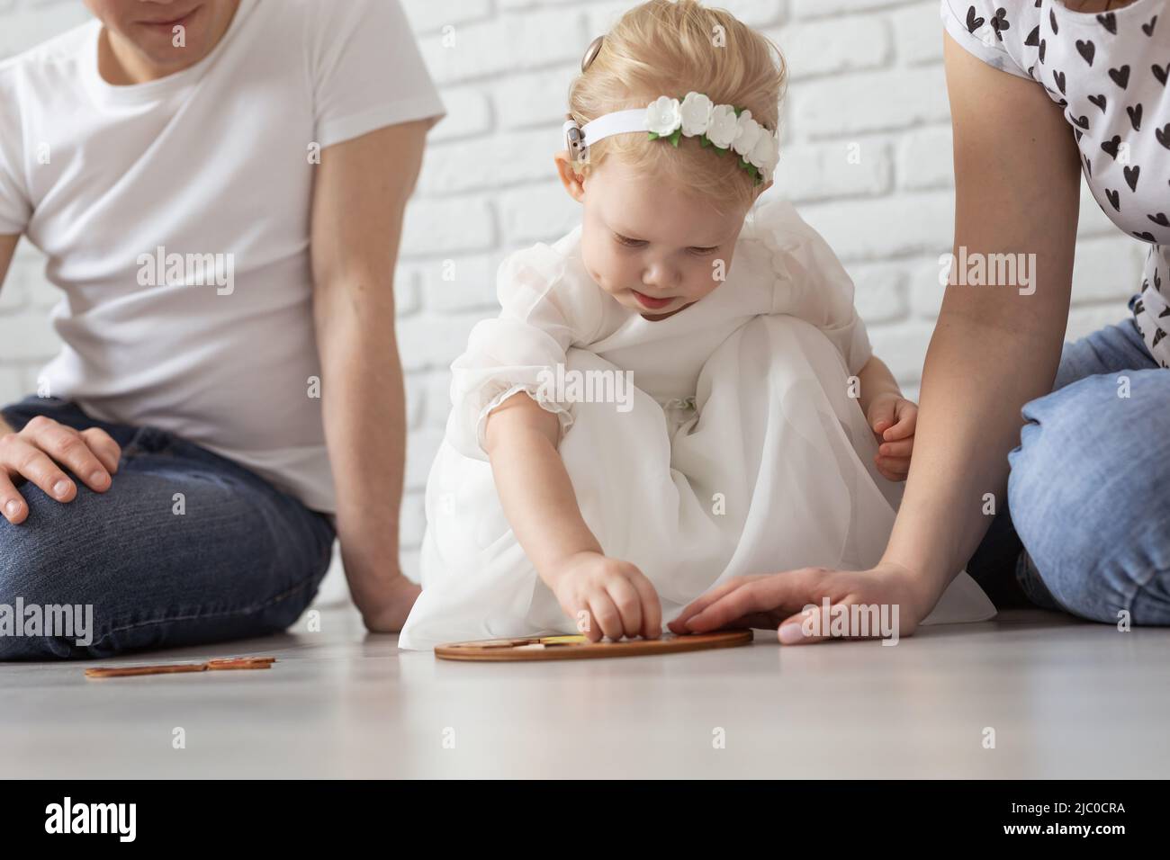 Baby child with hearing aids and cochlear implants plays with parents ...