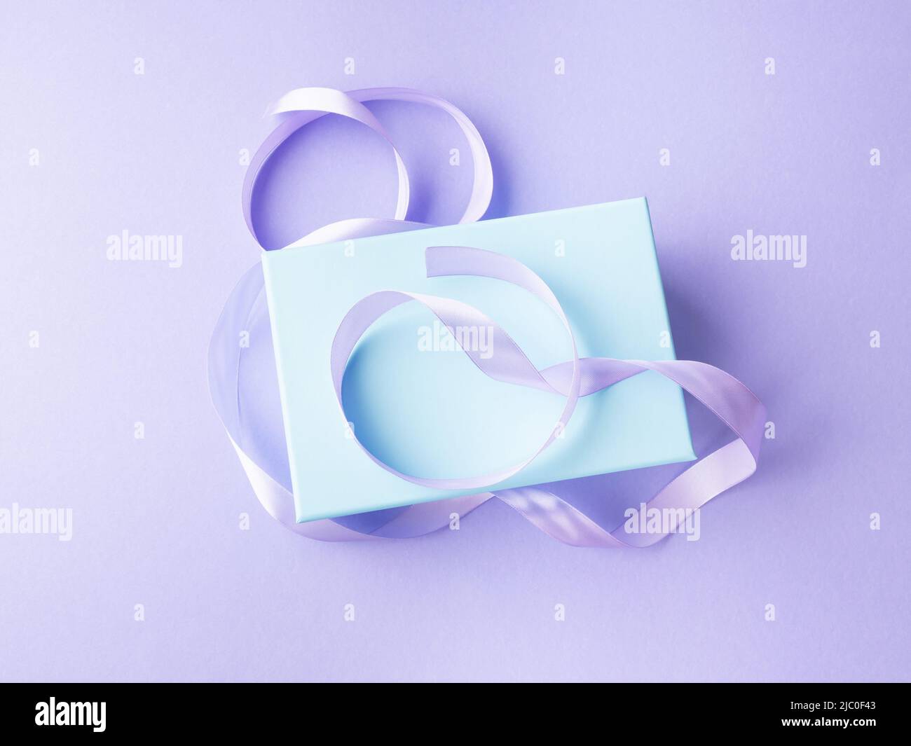 Wrapping blue pastel present box with ribbon on purple background Stock ...