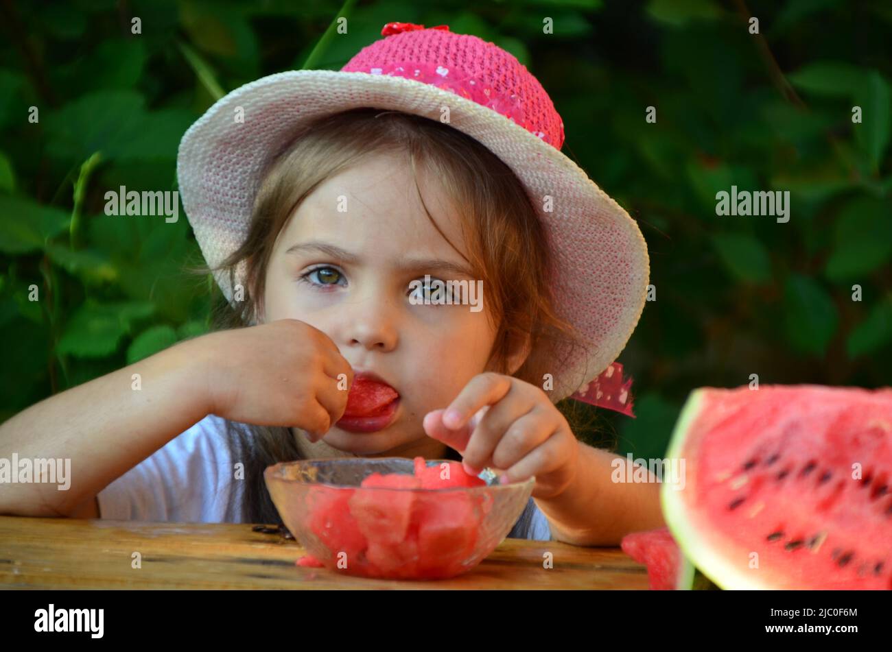Funny portrait of an incredibly beautiful little girl eating watermelon ...