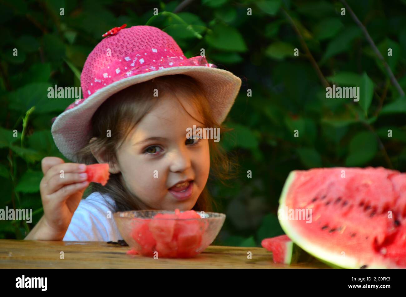 Funny portrait of an incredibly beautiful little girl eating watermelon ...