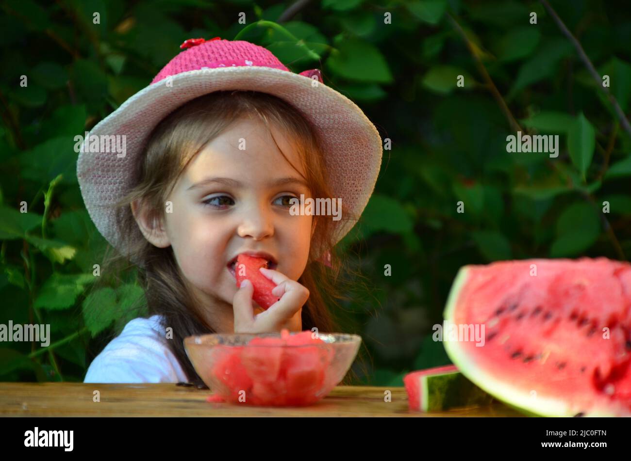 Funny portrait of an incredibly beautiful little girl eating watermelon ...