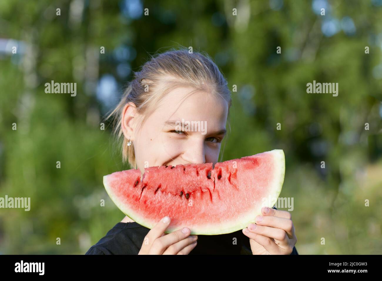 Happy Smiling Teenage Girl Eating Ripe Juicy Slice Of Watermelon In Outdoor On Green Nature