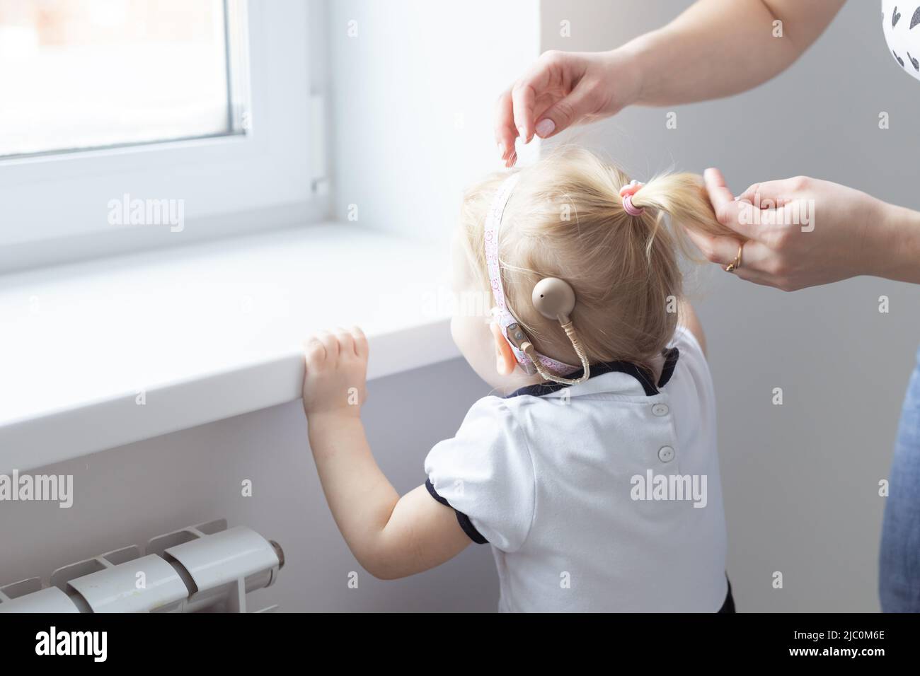 Mother fixing her daughter's cochlear implant hearing aid - deafness ...