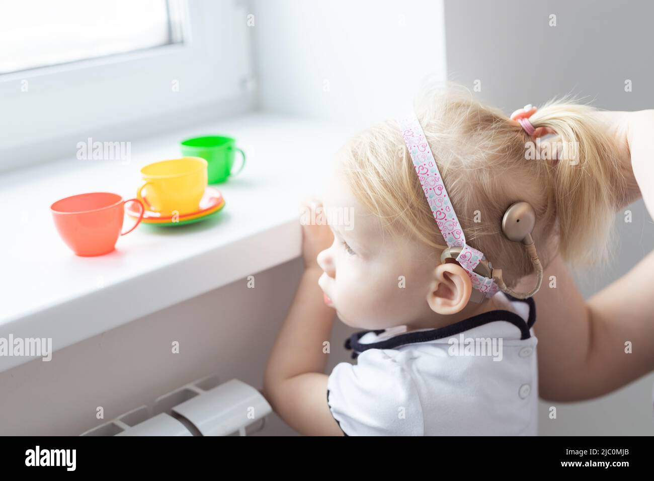 Mother fixing her daughter's cochlear implant hearing aid - deafness ...