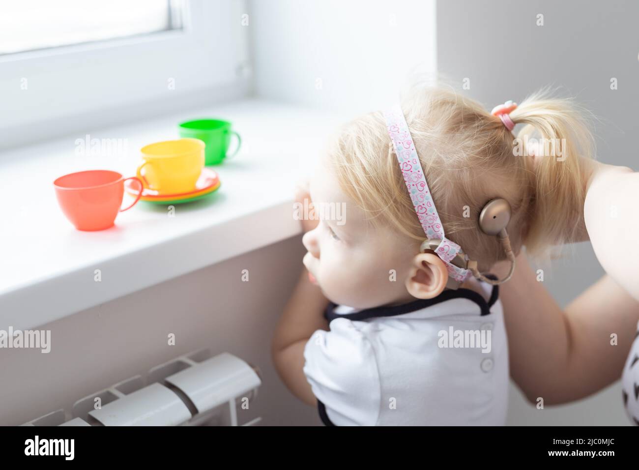 Mother fixing her daughter's cochlear implant hearing aid - deafness ...