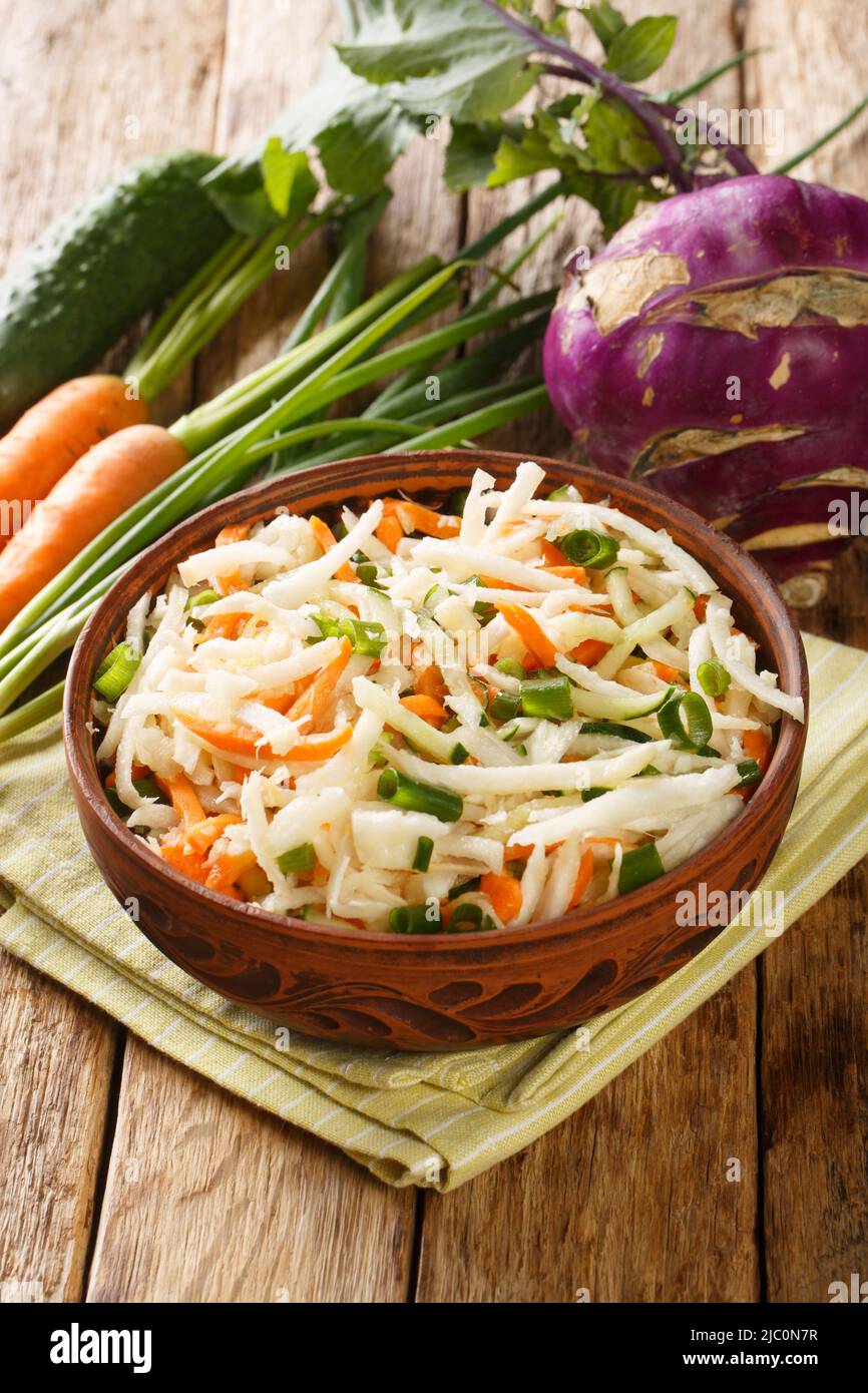 Fresh salad of kohlrabi, carrots, cucumbers and green onions close-up ...