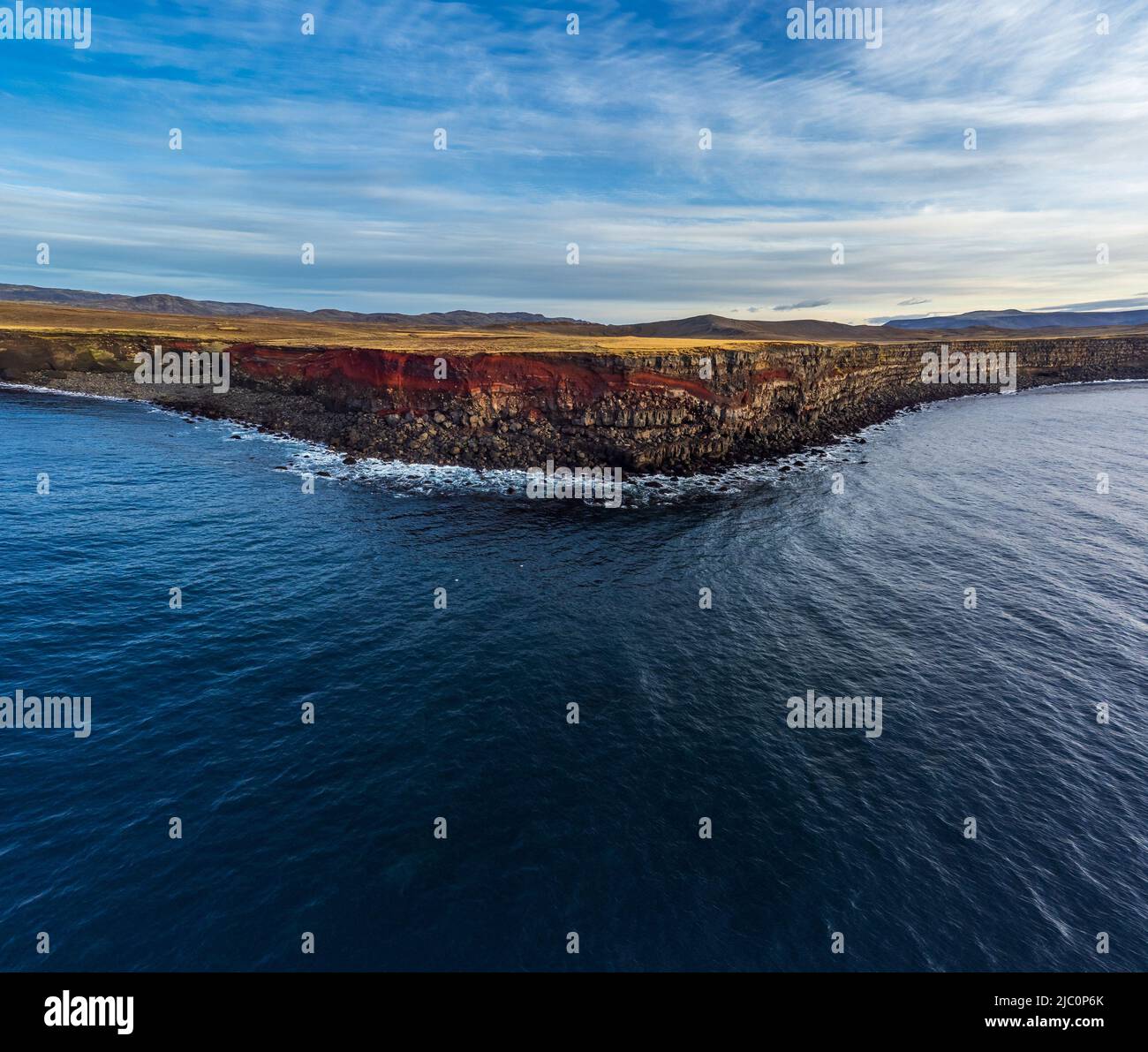 Steep cliffs with red seams in Iceland, view from the oceans Stock ...