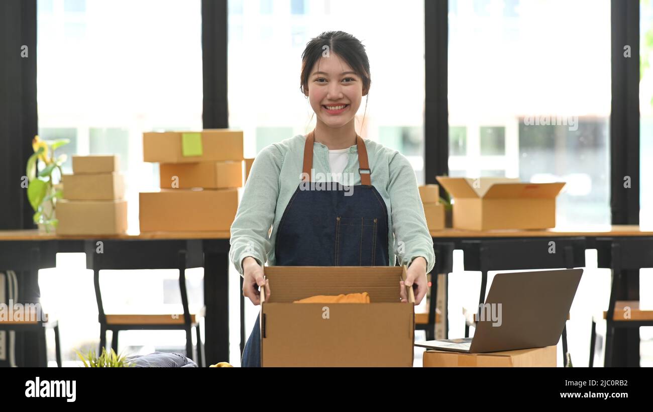 Startup small business owner wearing apron holding cardboard and ...