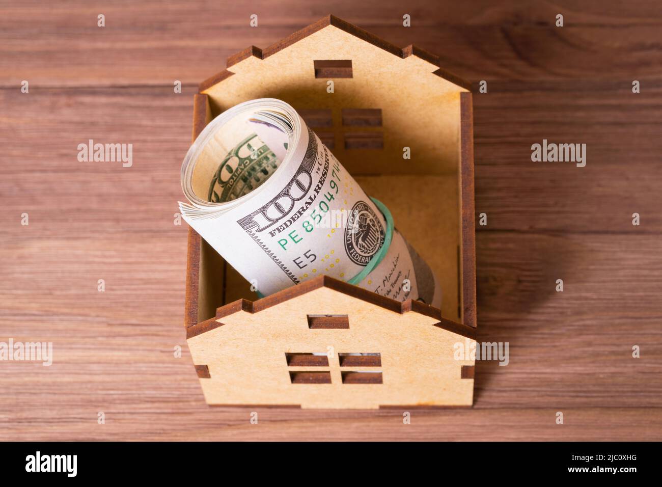 One hundred dollar bills cash roll inside a miniature wooden house ...